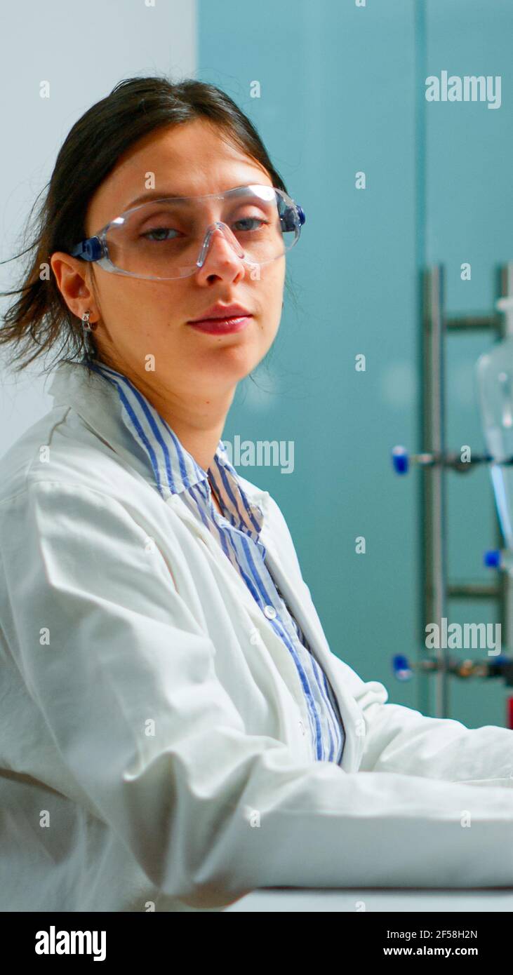 Portrait of tired scientist trying to smile at camera sitting in modern ...