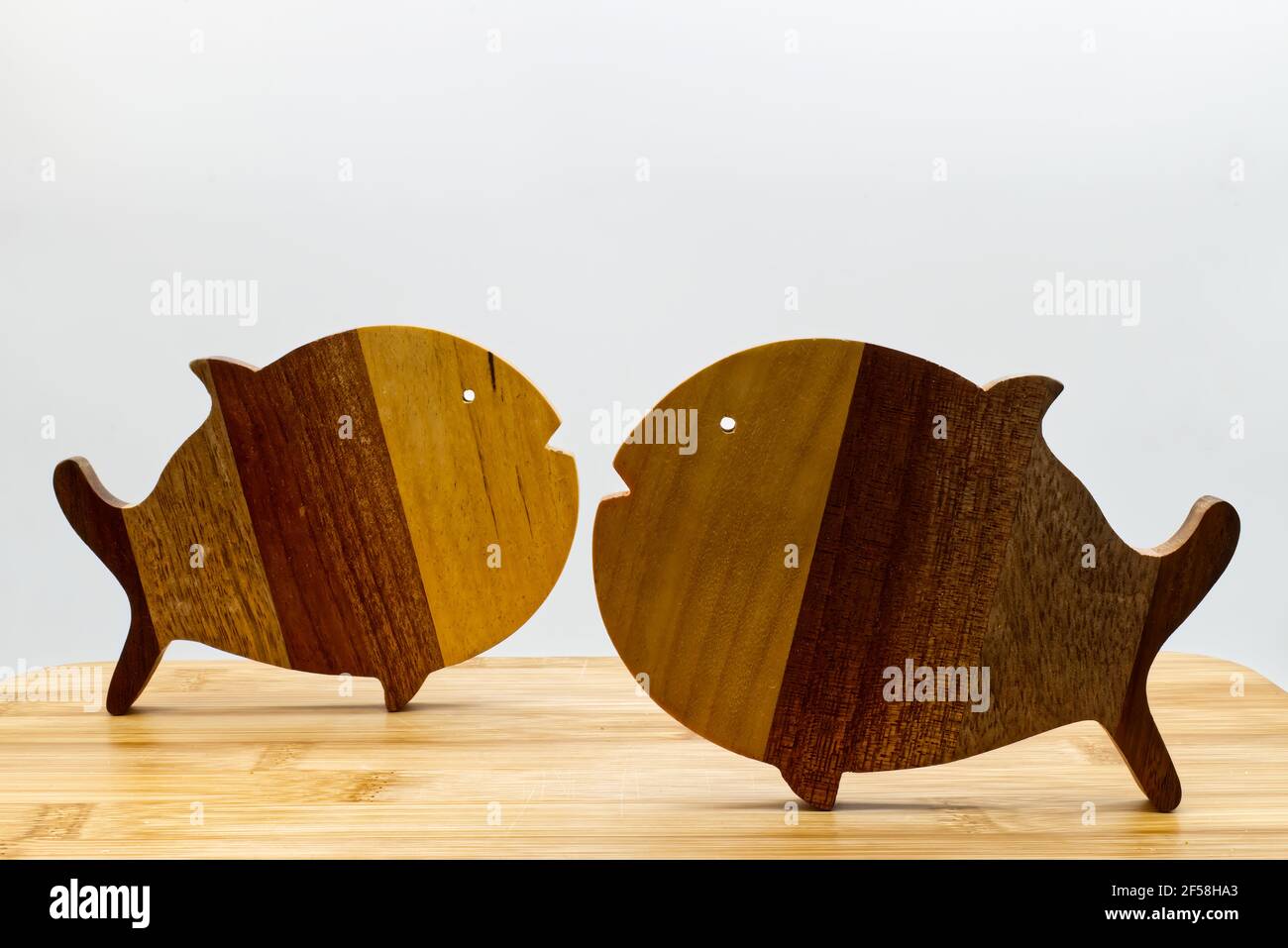 Wooden fish figures on wooden table, white background Stock Photo - Alamy