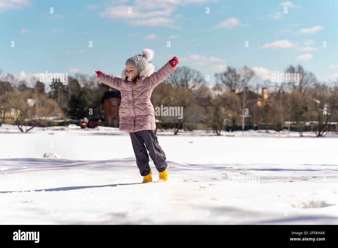 happy little girl jumping into a snowdrift with her arms spread out to ...