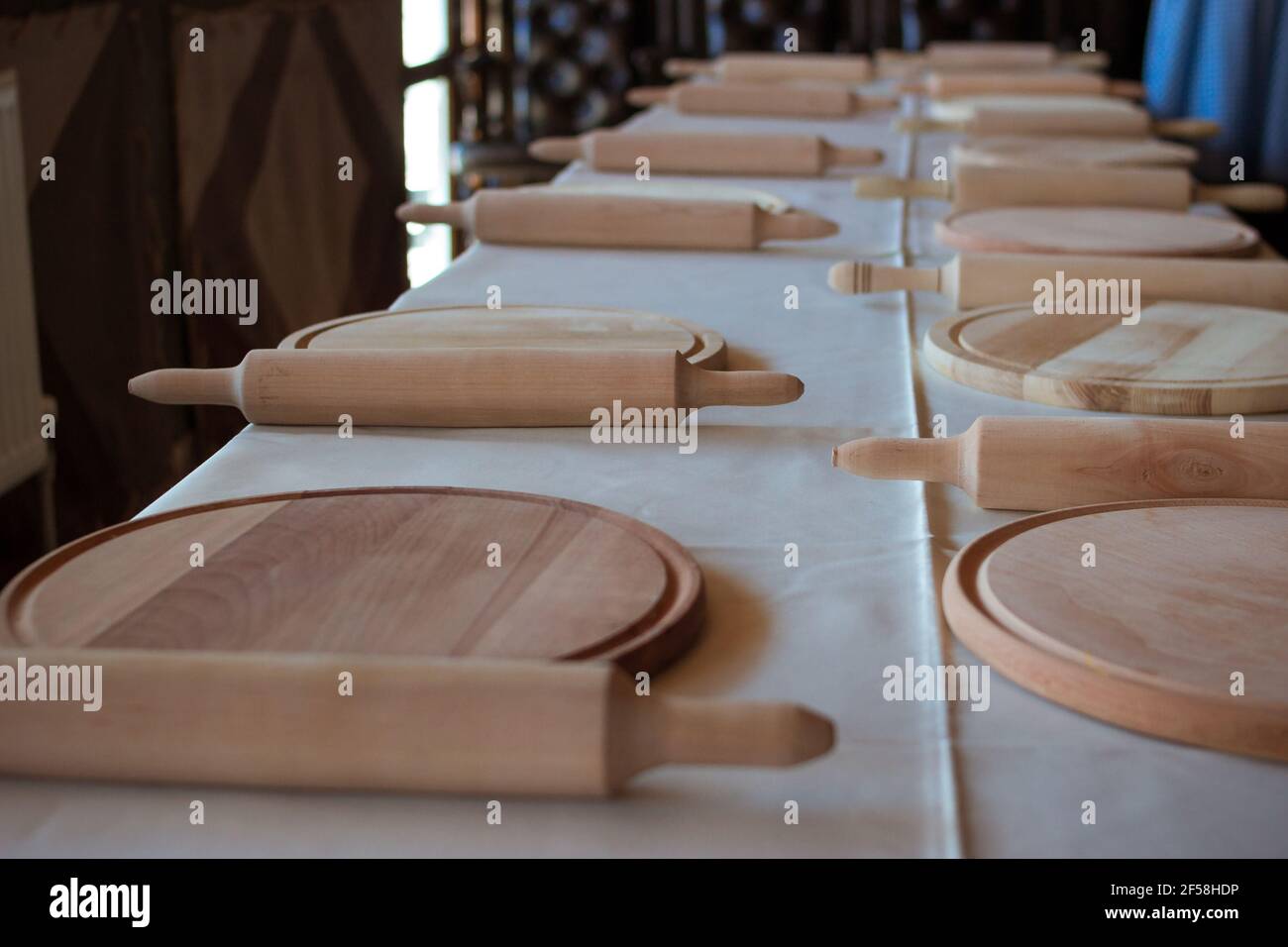 Wooden cutting boards and rolling pins on the long table with white ...