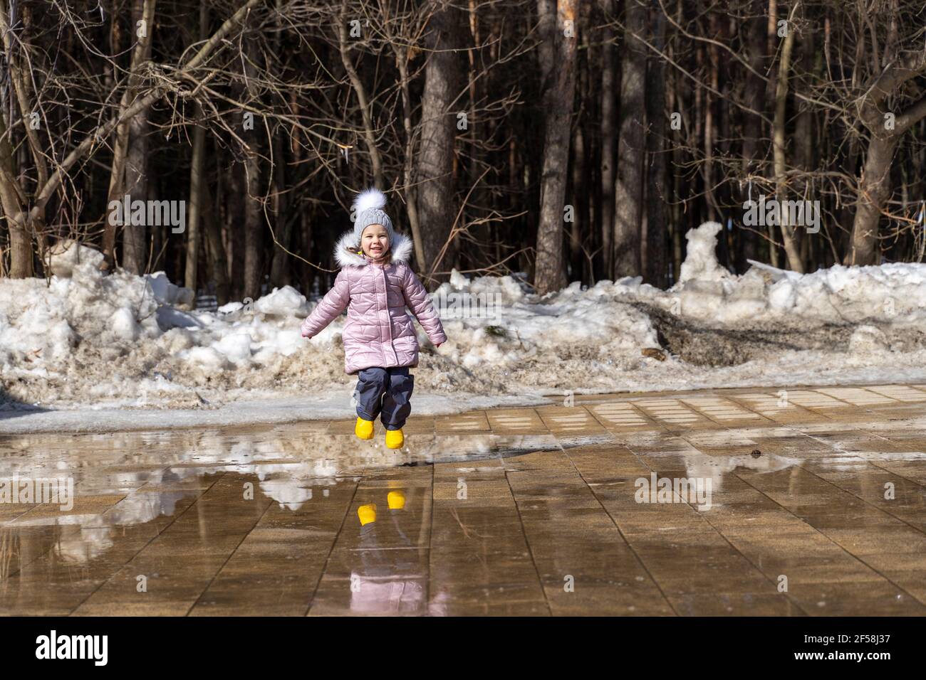 happy funny child girl playing in the spring puddles and laughing Stock ...