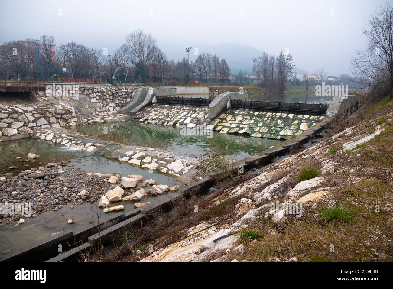 Small Rock Dam of a River in a Built-up Area Stock Photo - Alamy