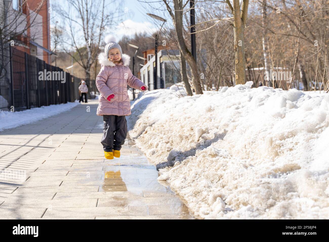 happy child girl jumping on spring puddles and laughing Stock Photo - Alamy