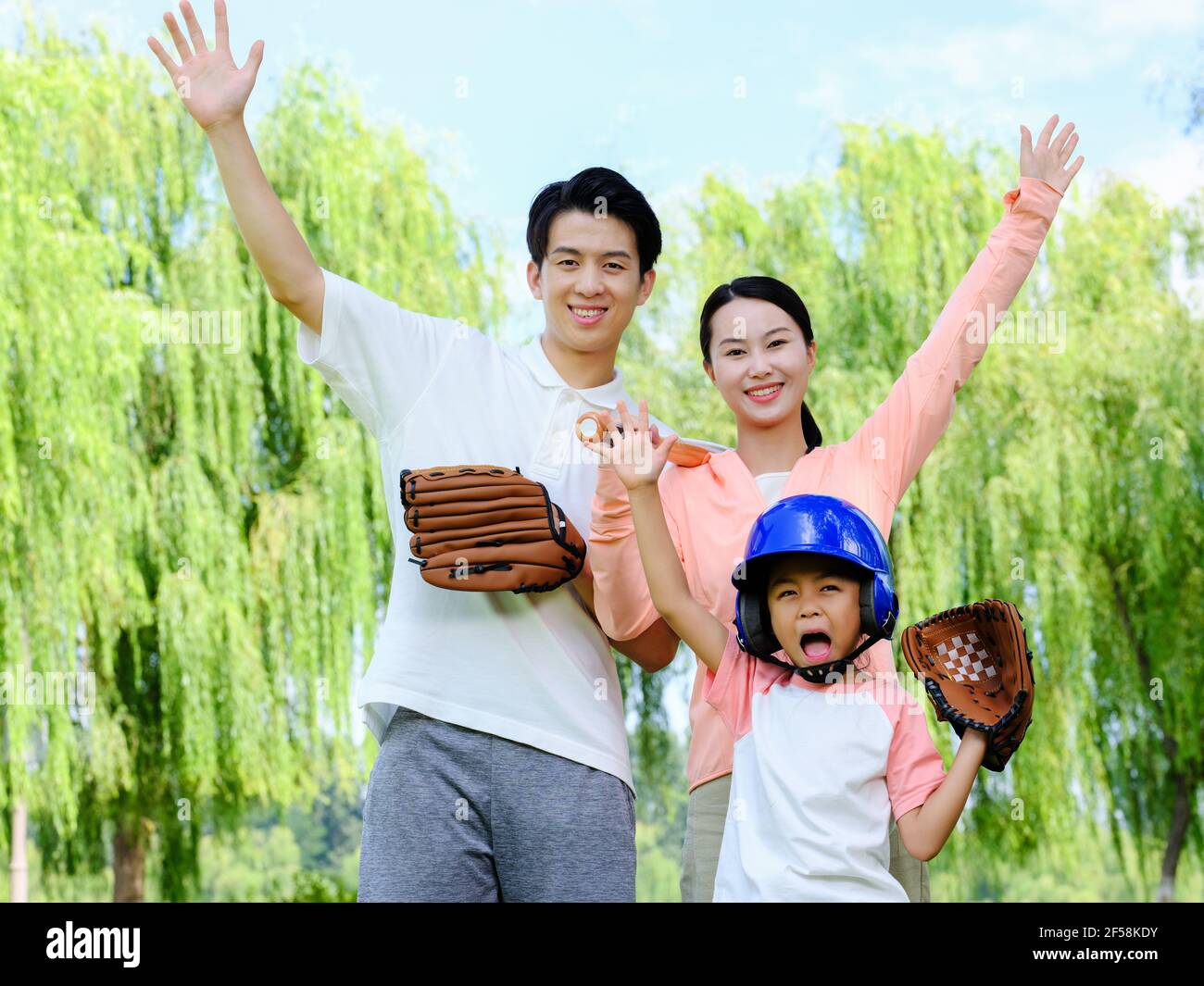 Happy family of three playing baseball in the park,Arms raised Stock ...