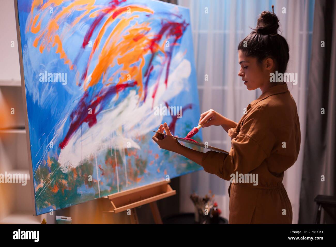Young artist mixing paint on wooden palette in art studio. Modern ...
