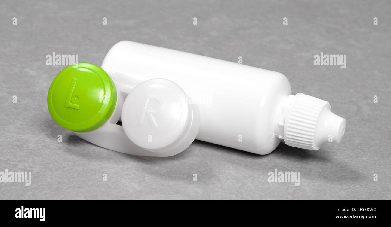 Green contact lens case and bottle of solution, isolated on grey ...