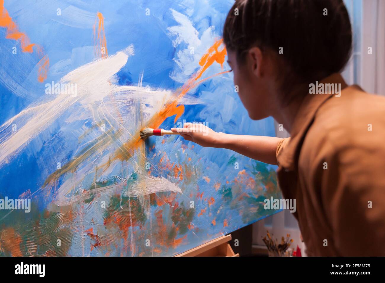 Woman working on details on large canvas in art studio. Modern artwork ...