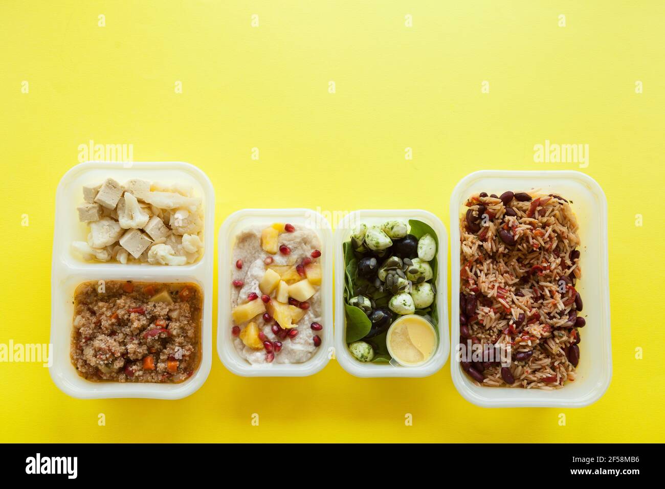 Plastic containers with delicious food over yellow background. Take ...