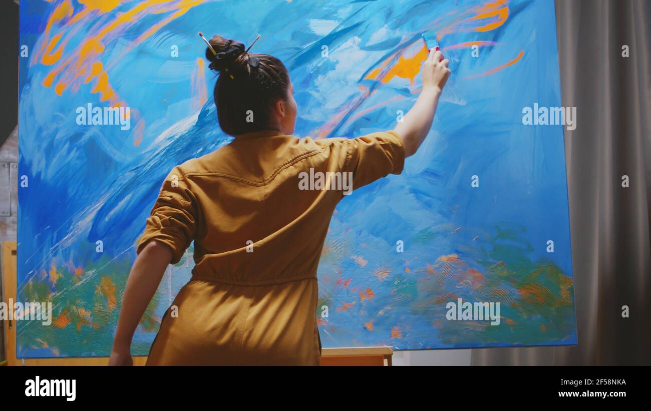 Innovative female painter using orange paint on big canvas Stock Photo ...