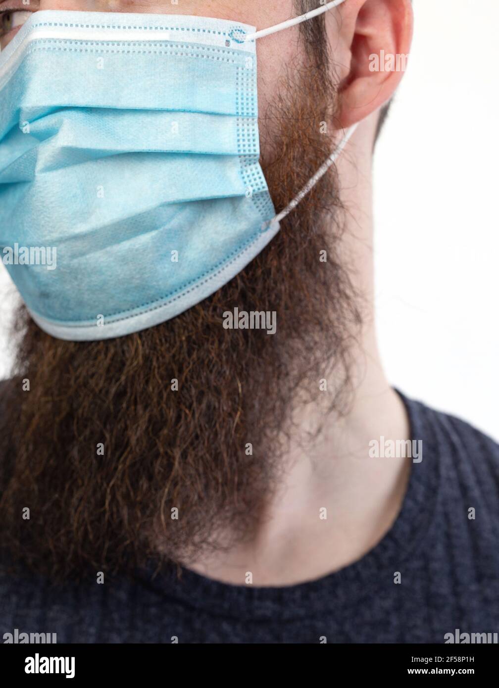 Caucasian young bearded adult man wearing a protective or surgical mask ...