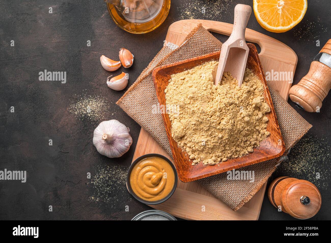 Dry mustard powder and ready-made mustard on a brown background with ...