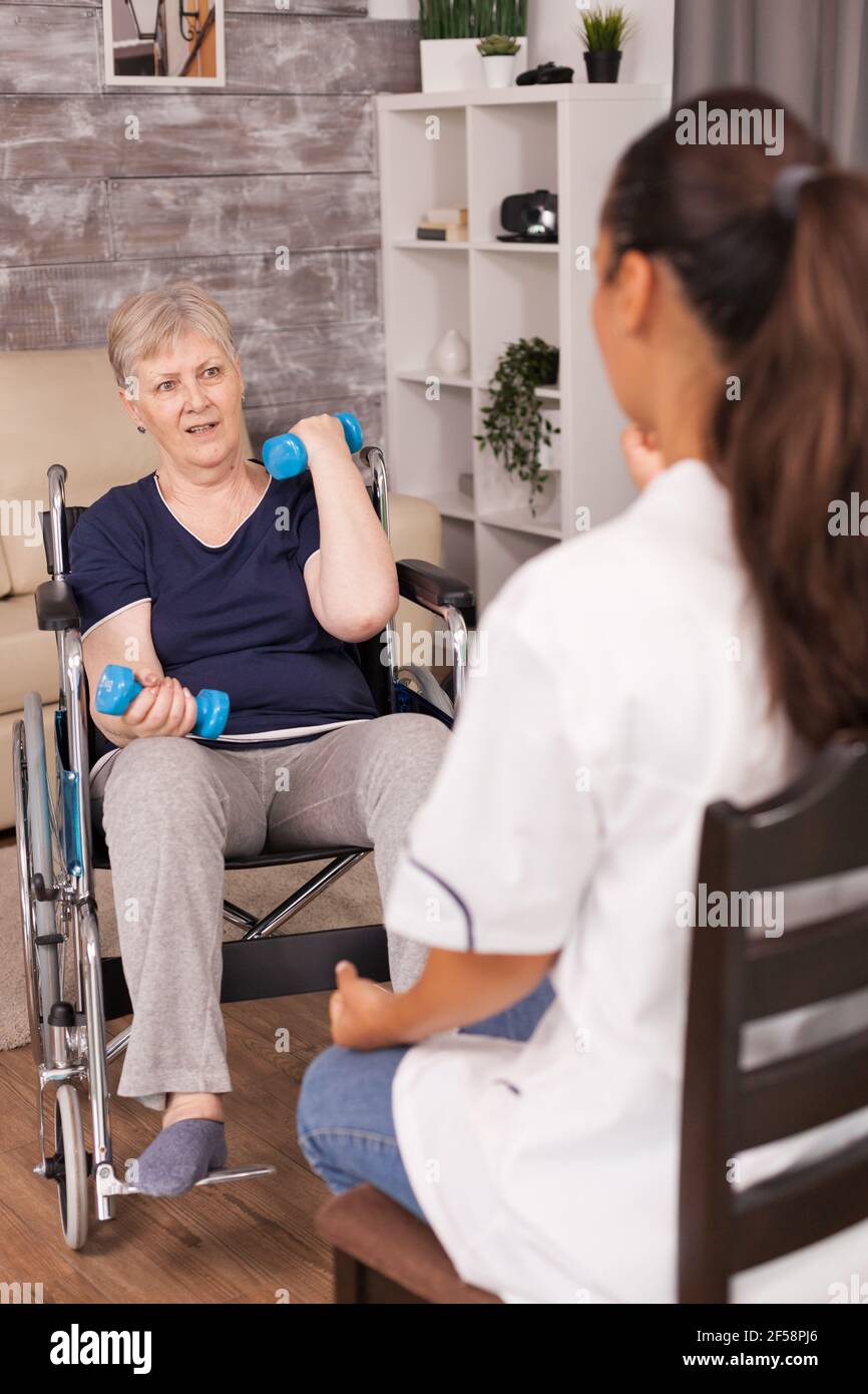 Old lady in wheelchair holding weights for recovery. Disabled ...
