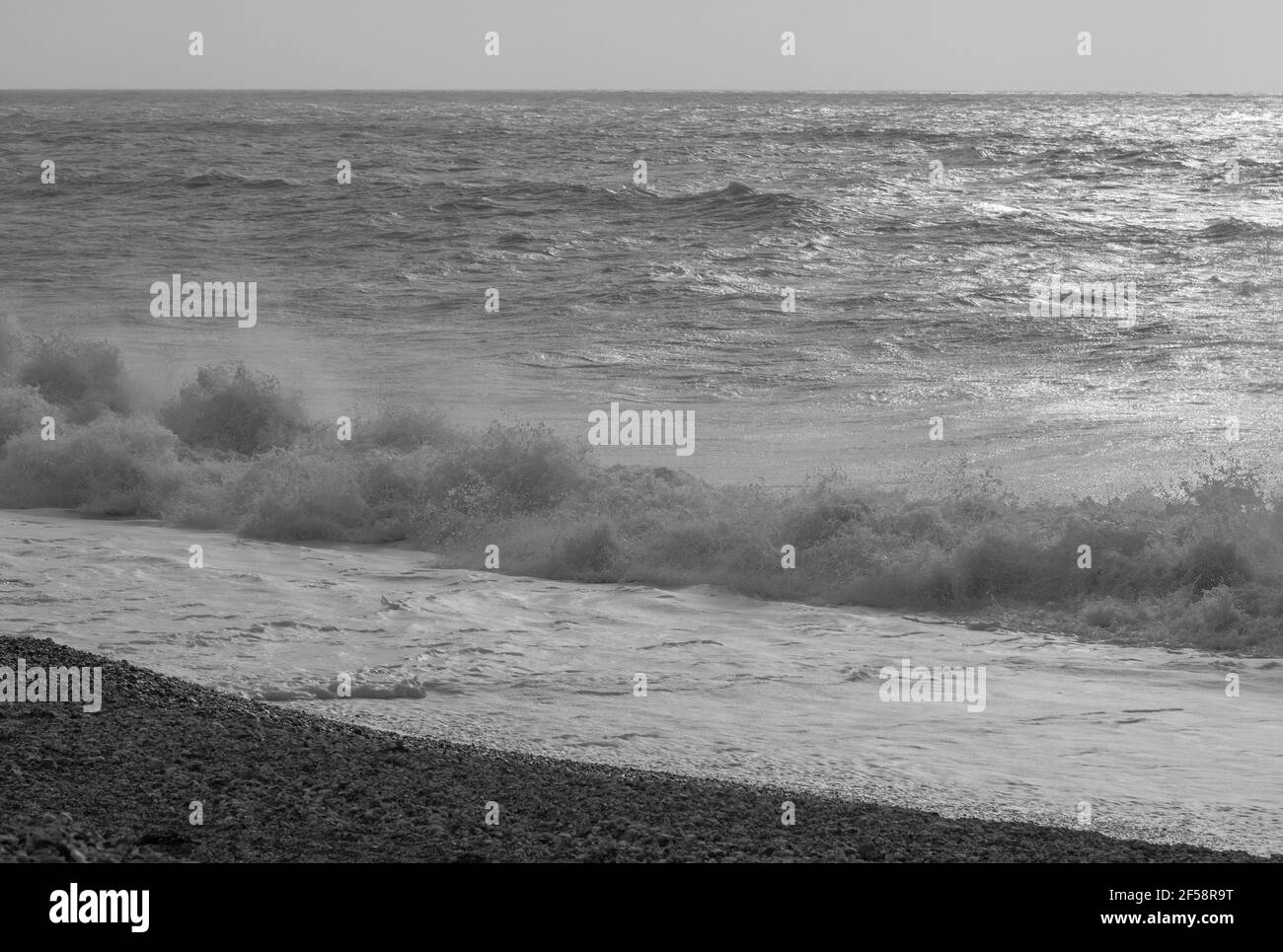 Waves of a choppy sea seen braking on the shoreline of an English beach ...
