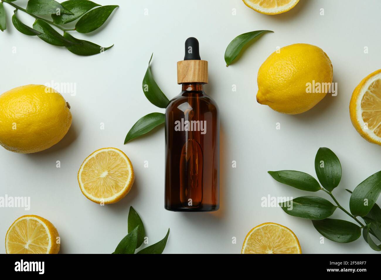 Dropper bottle with oil, lemons and leaves on white background Stock Photo - Alamy