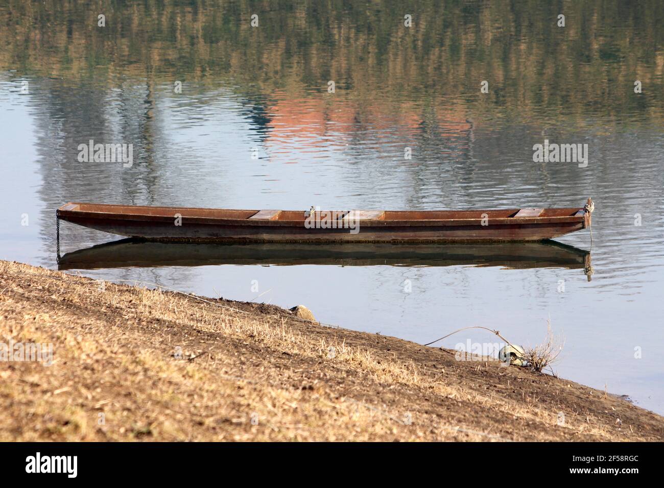 Elongated old dilapidated light brown wooden river boat made from ...