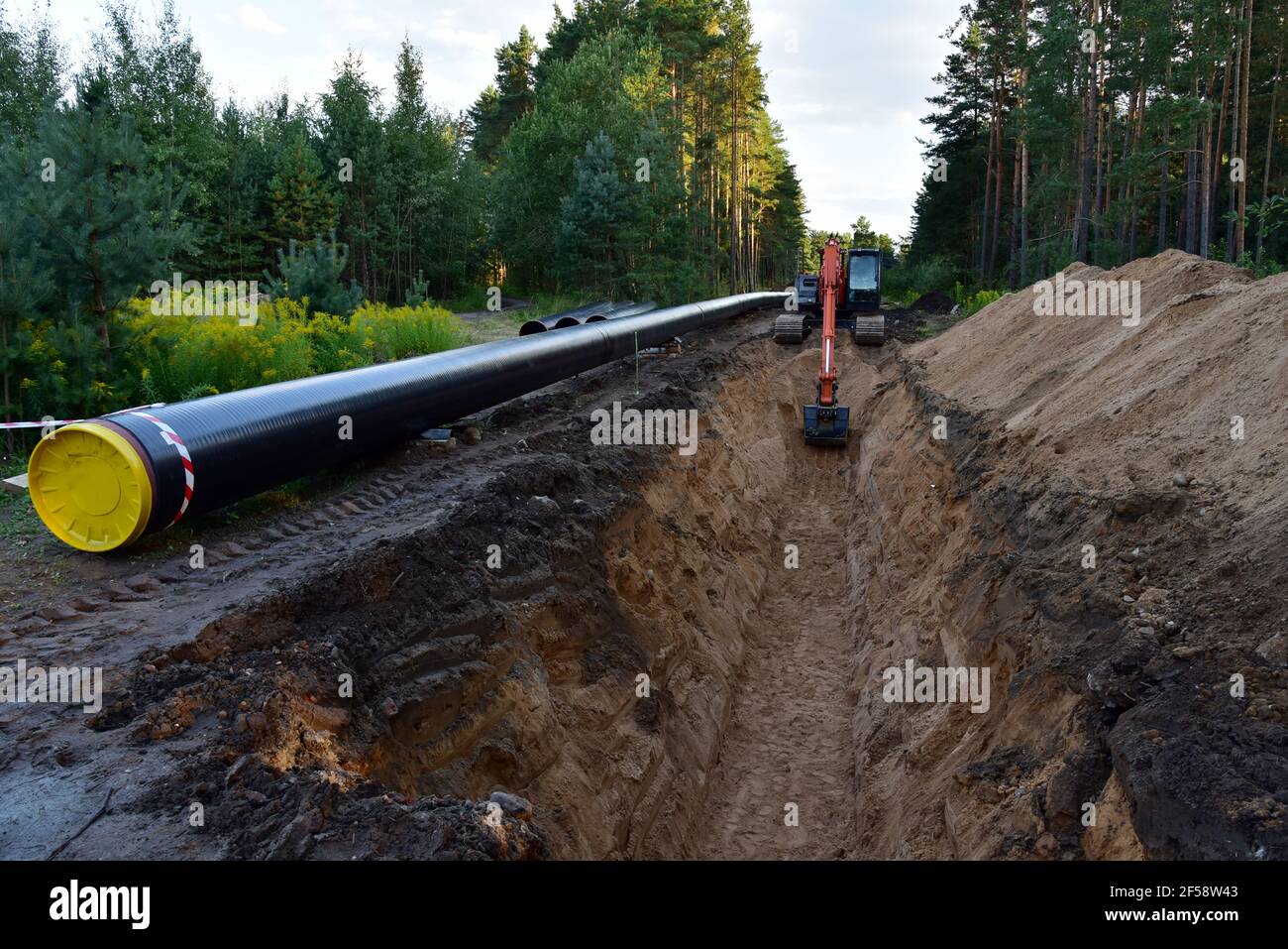 Excavator digging trench in ground for laying pipeline of natural gas ...