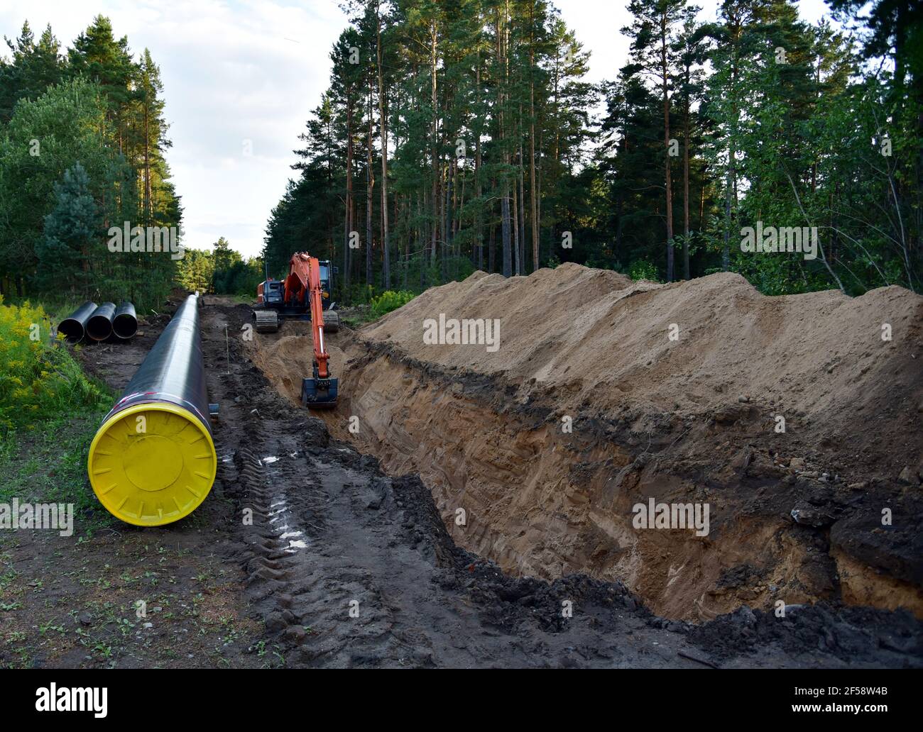 Excavator digging trench in ground for laying pipeline of natural gas ...