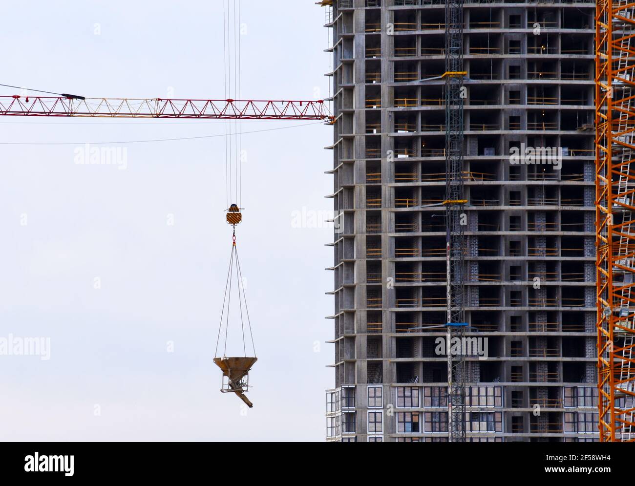 Tower crane lifting a concrete bucket for pour of concrete into ...