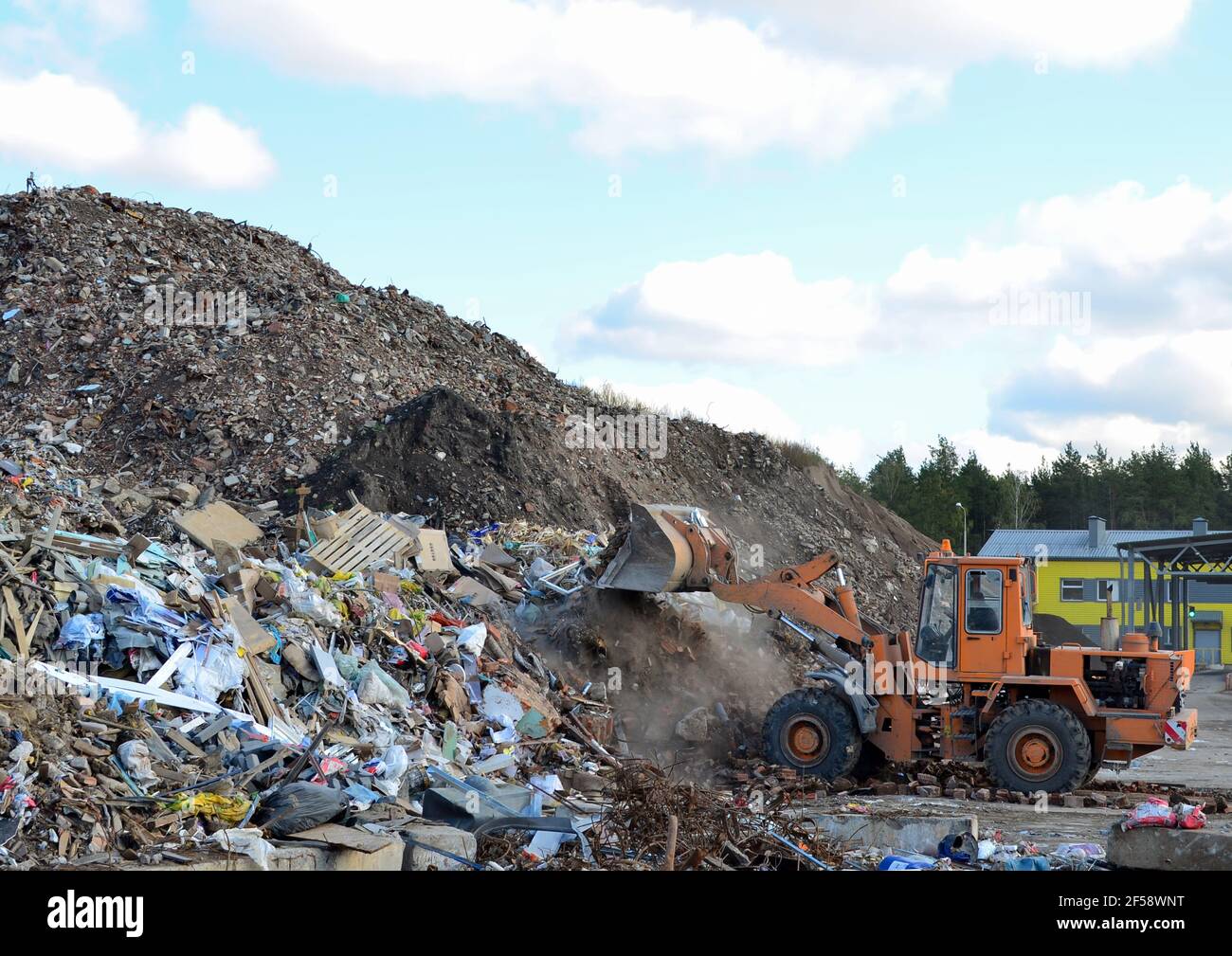 Front-end loader works in a landfill for the disposal of construction ...
