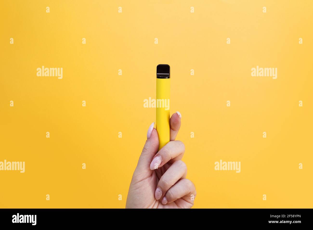 Yellow disposable electronic cigarette in female hand. Bright yellow ...