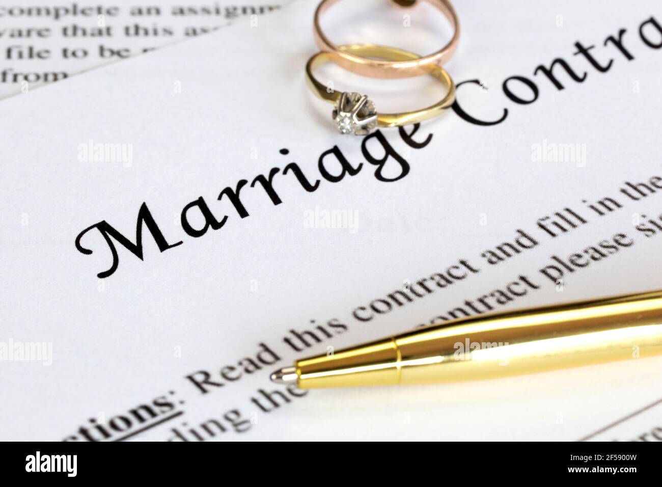 Marriage contract with two golden wedding rings and gold pen ...