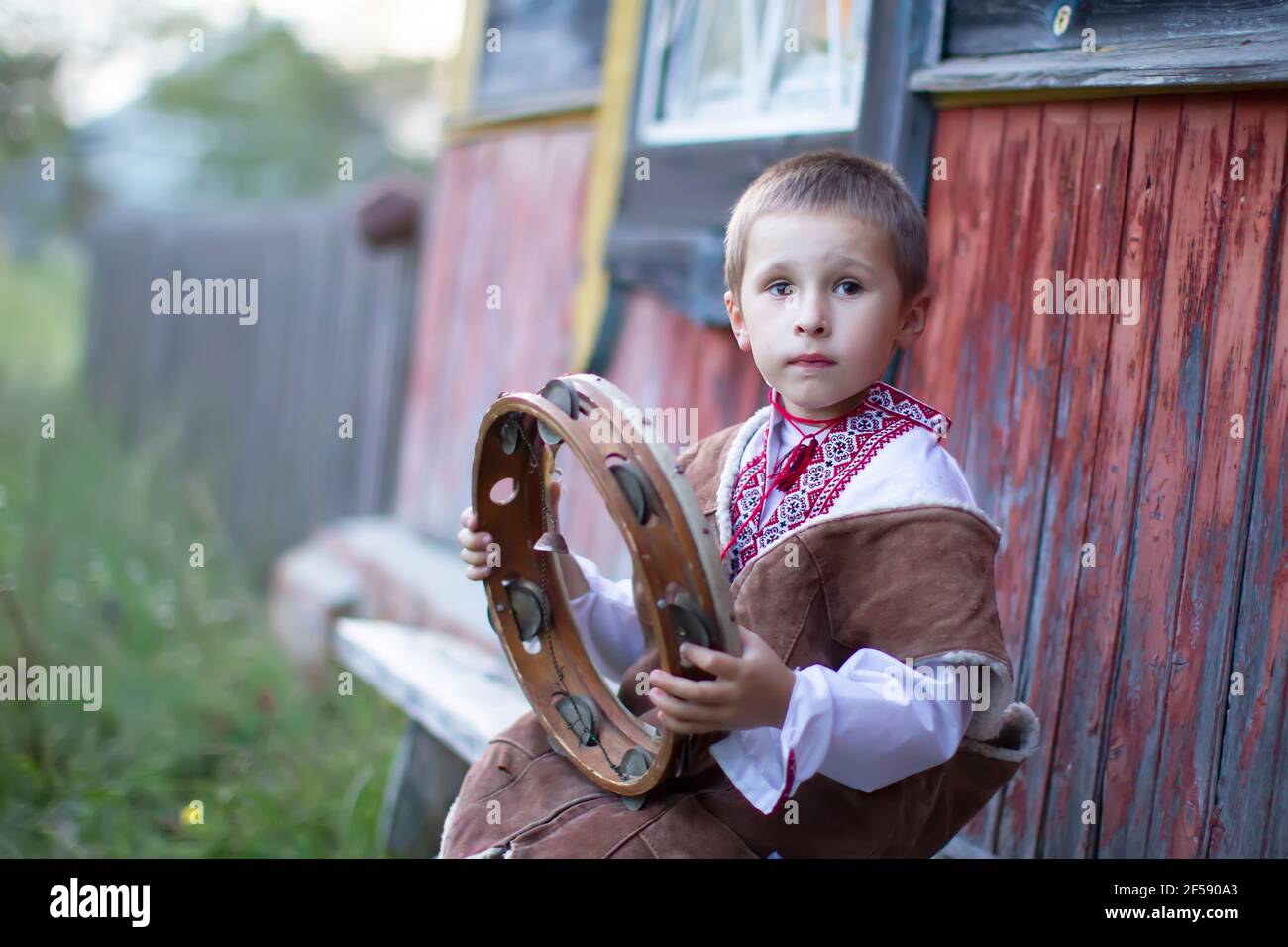 Little boy in Slavic national dress with an ethnic tambourine. A ...