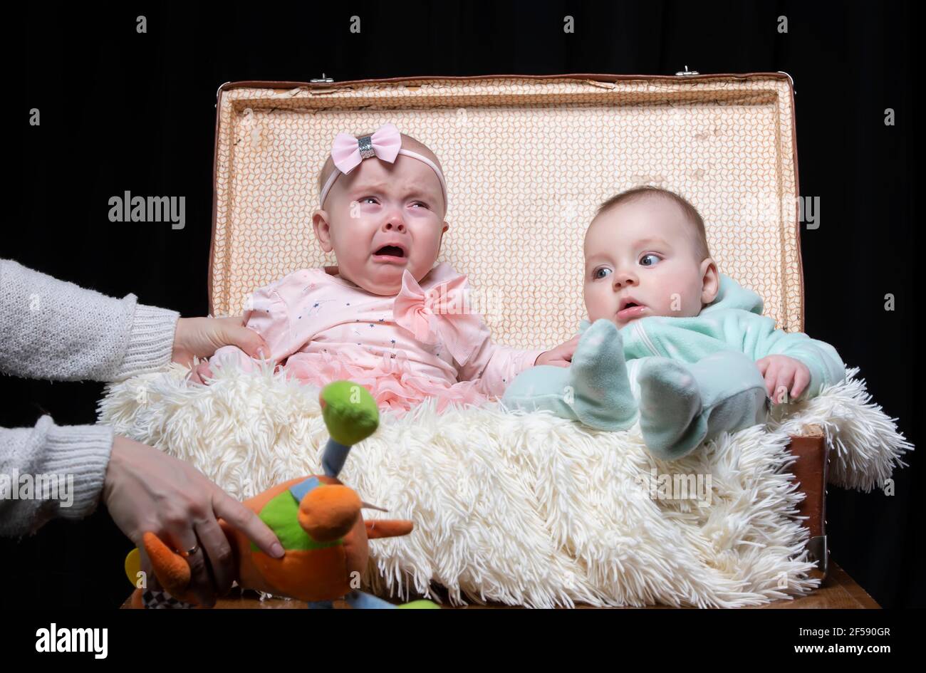 A little boy and a crying baby are sitting in a retro suitcase ...
