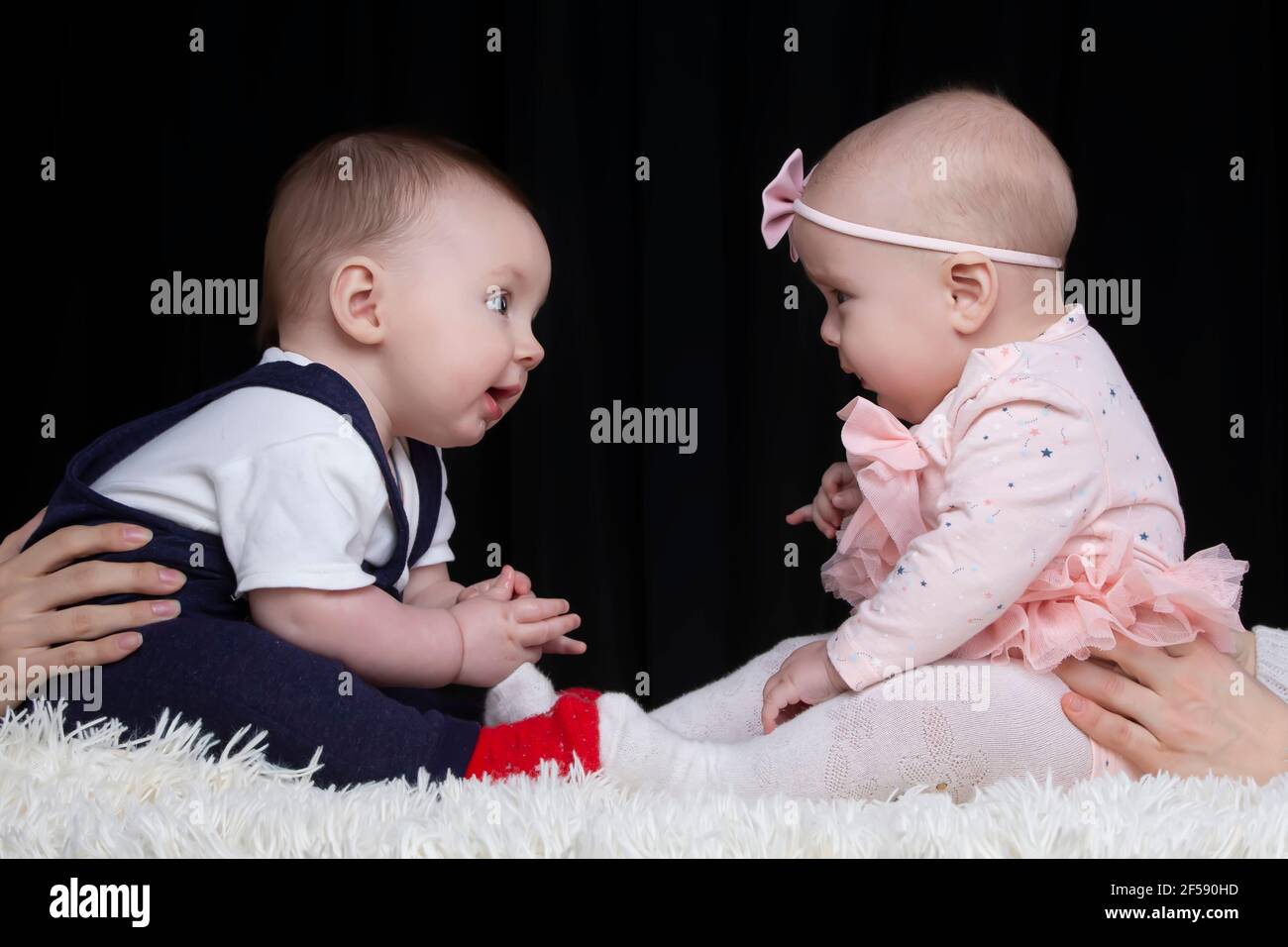 Funny little boy and girl are sitting opposite each other. Brother and ...