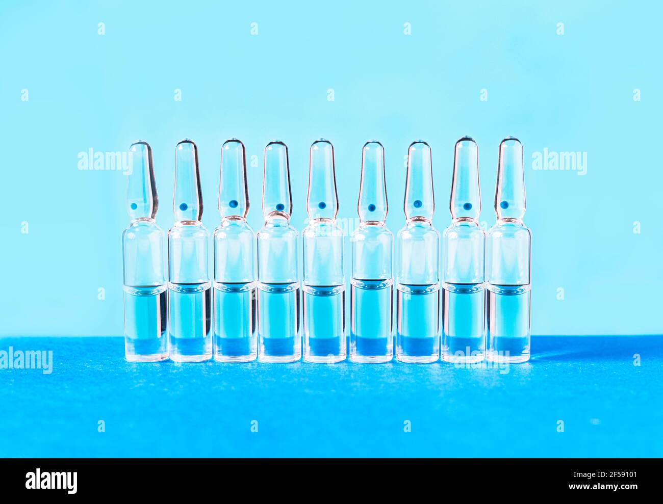 Medical ampoules for injection on a blue background. Scattered glass ...