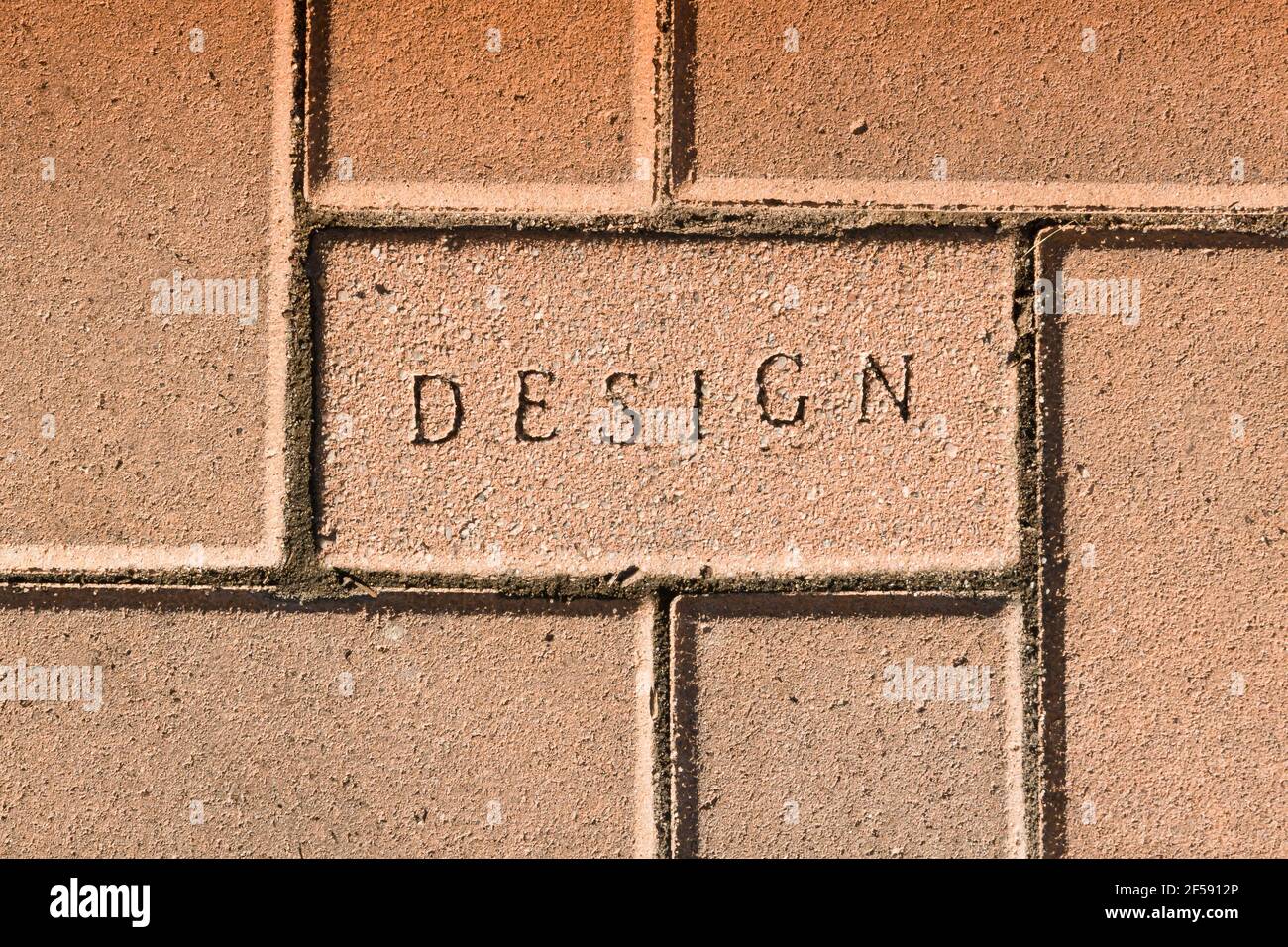 The word design stamped in the surface of brick paving a building and ...