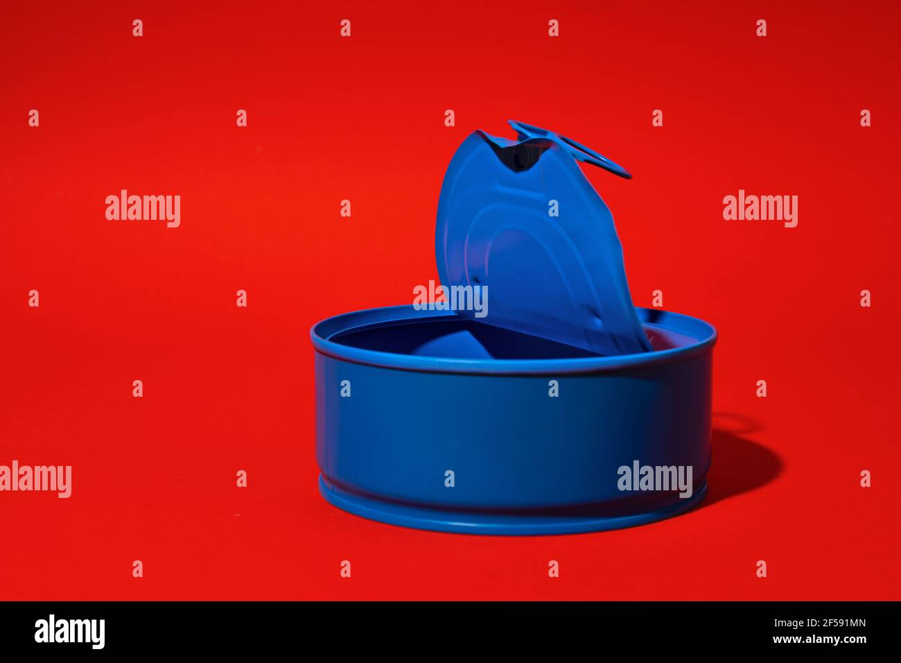 Blue tin can on dark red background Stock Photo - Alamy