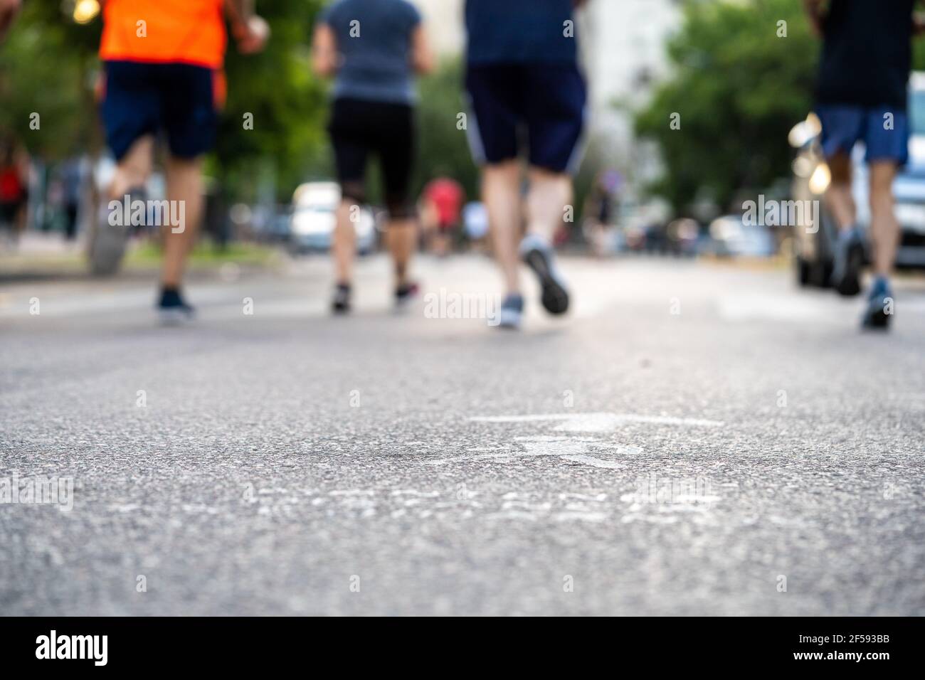 Selective focus of the road with people running on the blurry ...