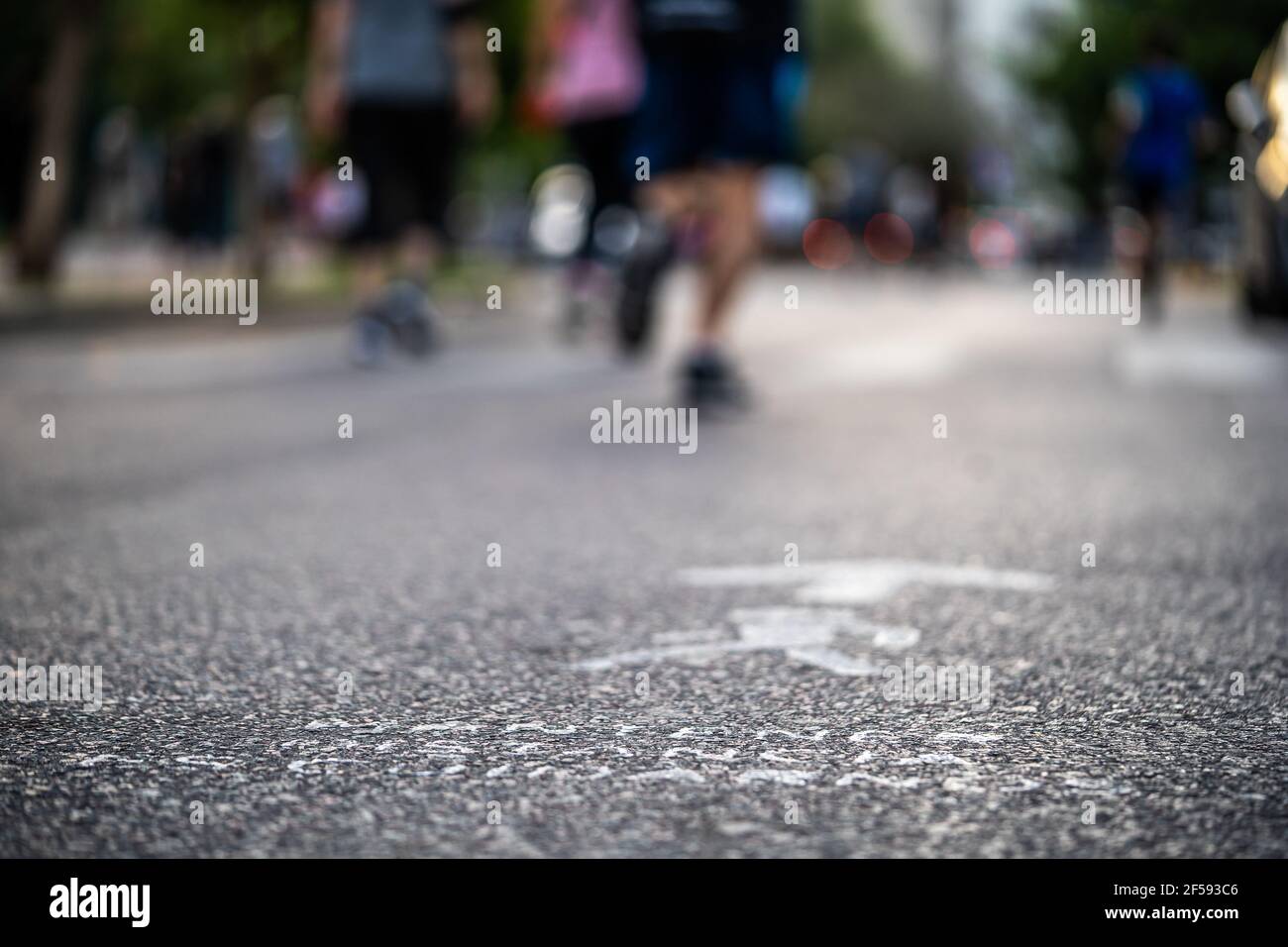 Selective focus of the road with people running on the blurry ...