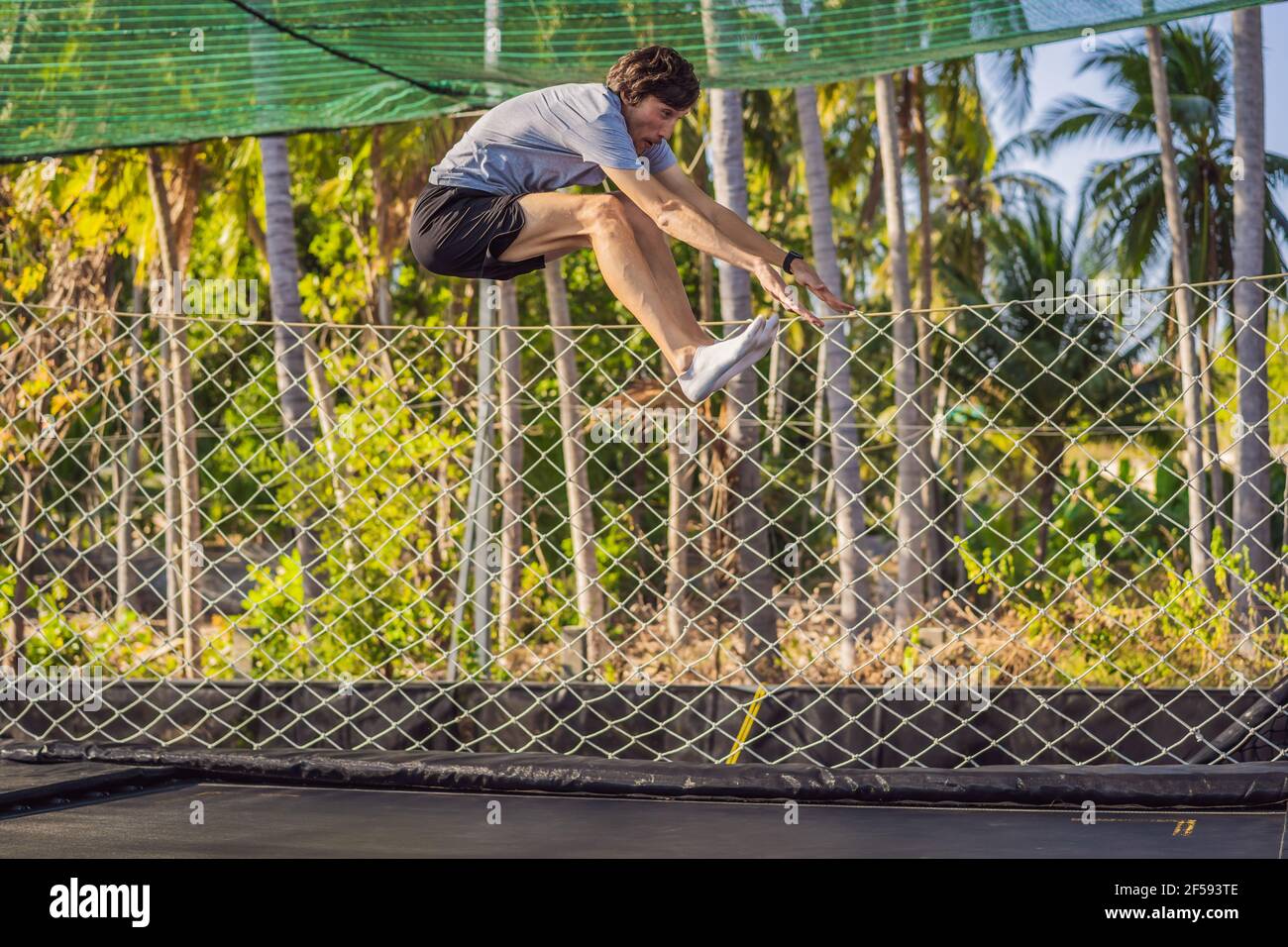 Happy man jumping on an outdoor trampoline, against the backdrop of ...