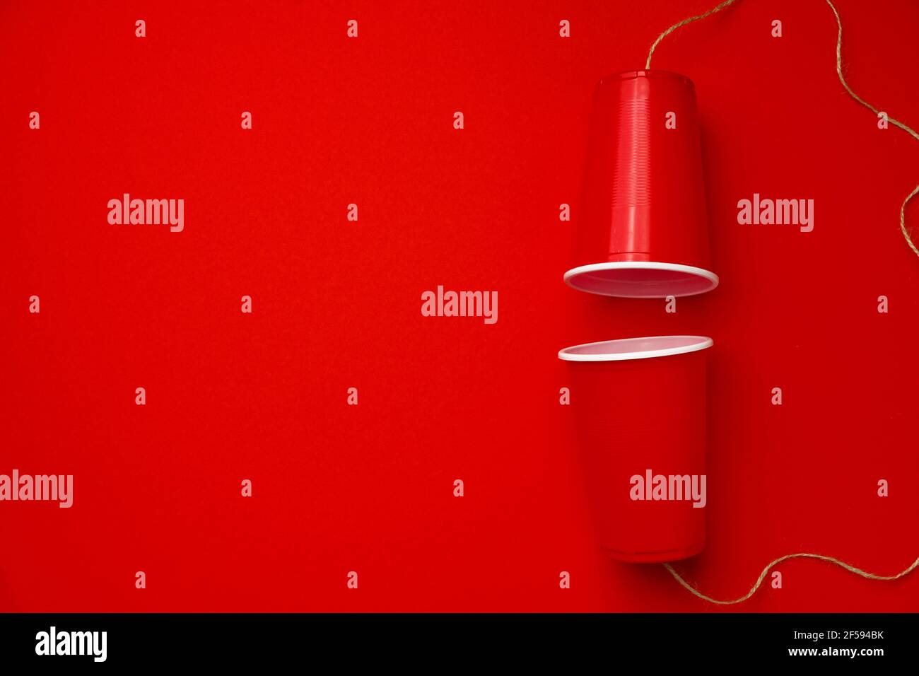 Red plastic cups connected with a thread on red background Stock Photo ...