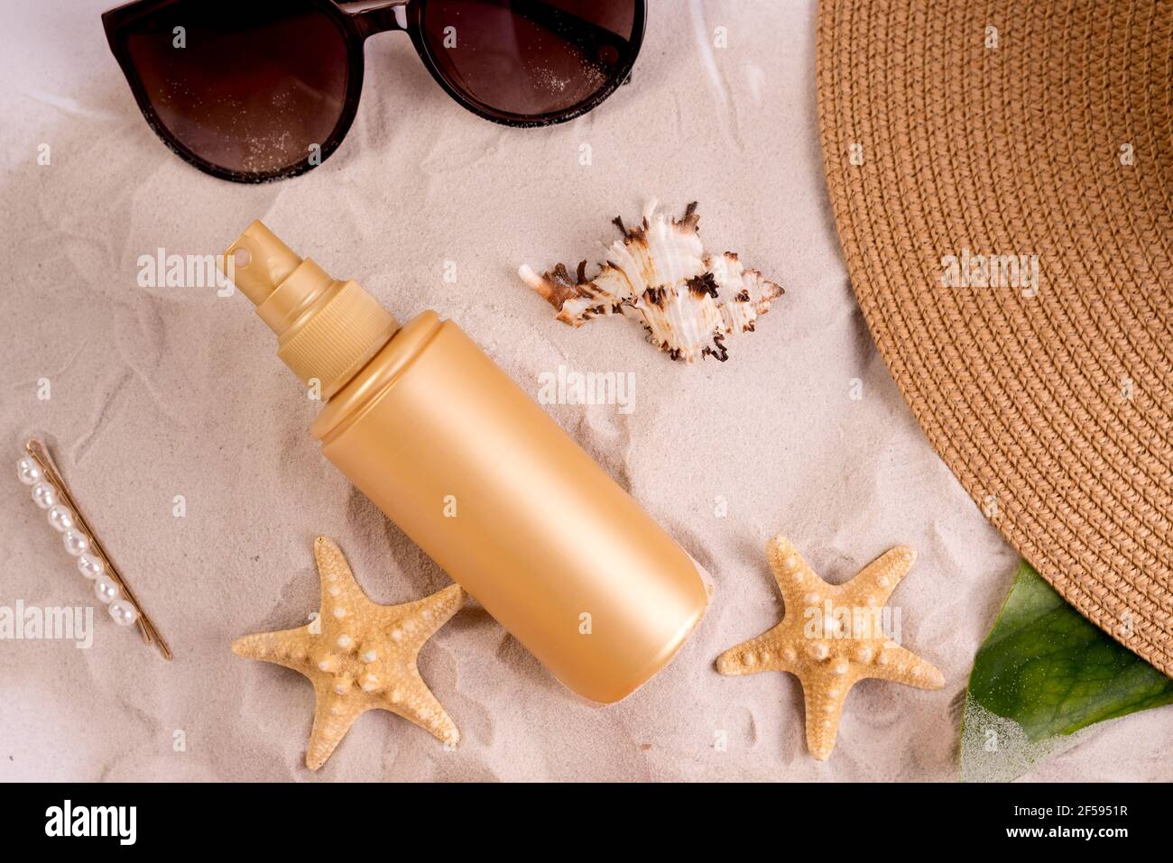 Sunscreen spray bottle on a sandy beach decorated with different ...