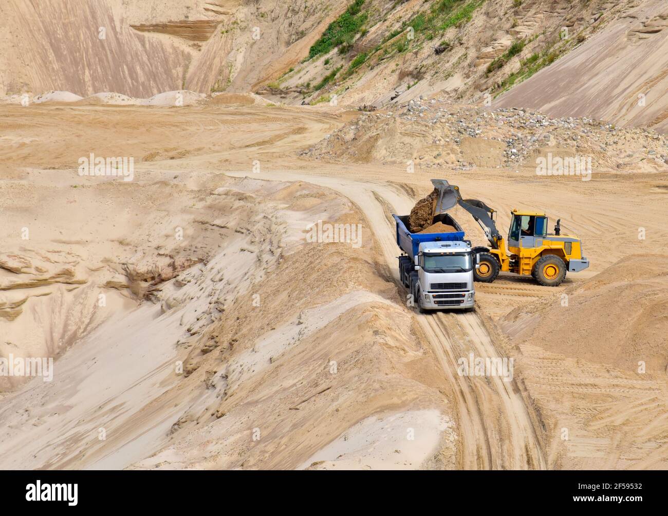 Wheel front-end loader loading sand into heavy dump truck at the ...