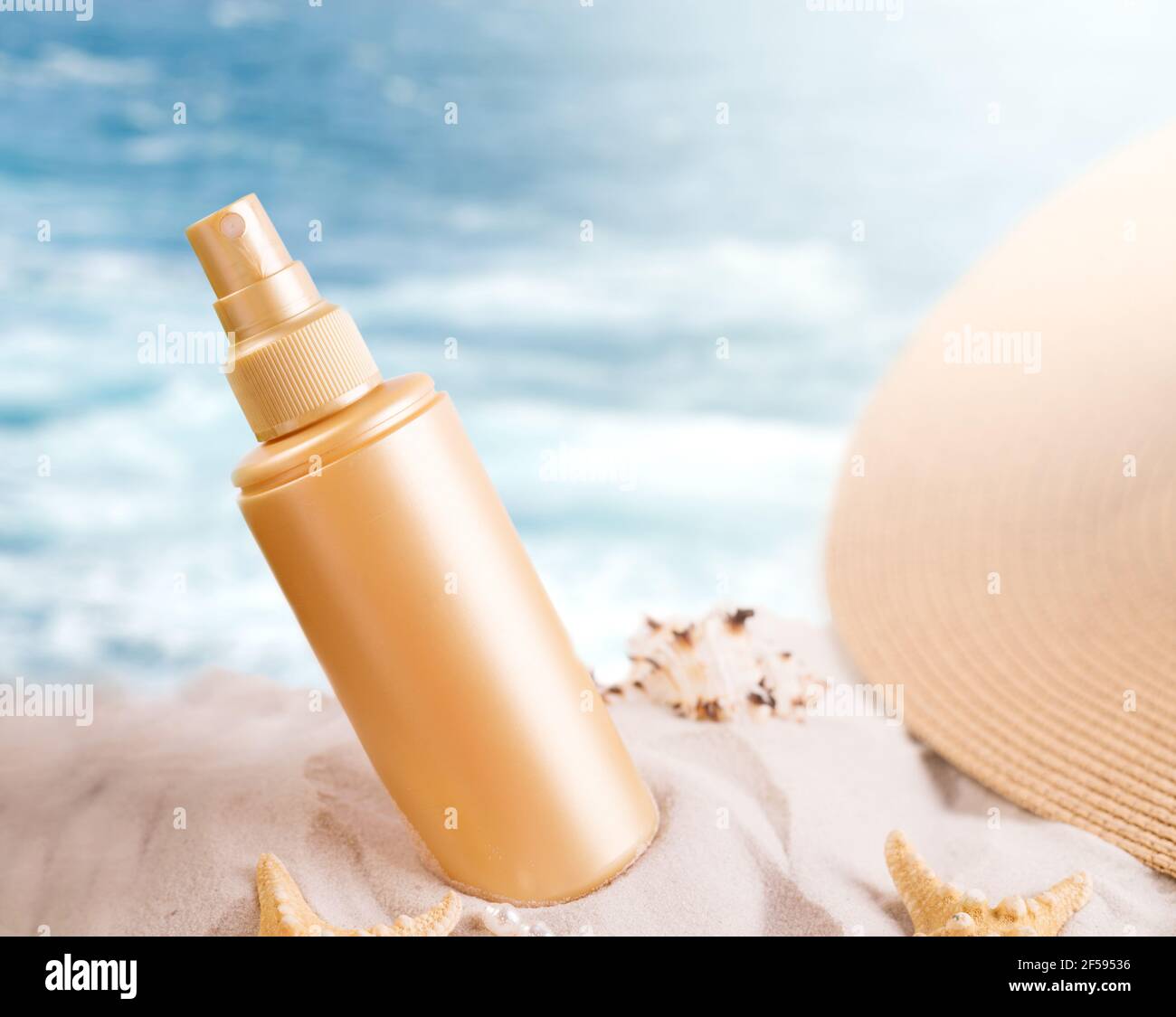 Sunscreen spray bottle on a sandy beach decorated with different ...