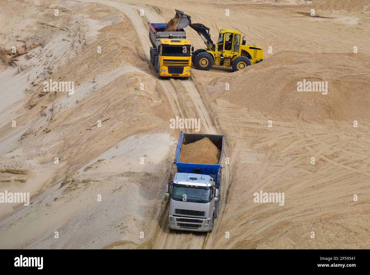Wheel front-end loader loading sand into heavy dump truck at the ...