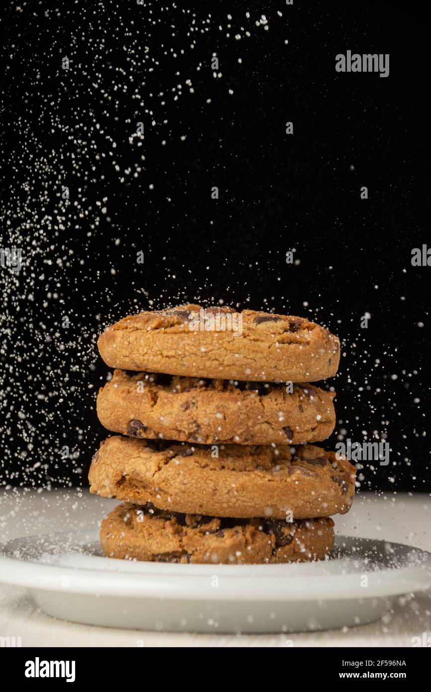 Close-up of stack of chocolate cookies on plate, with falling sugar, on ...