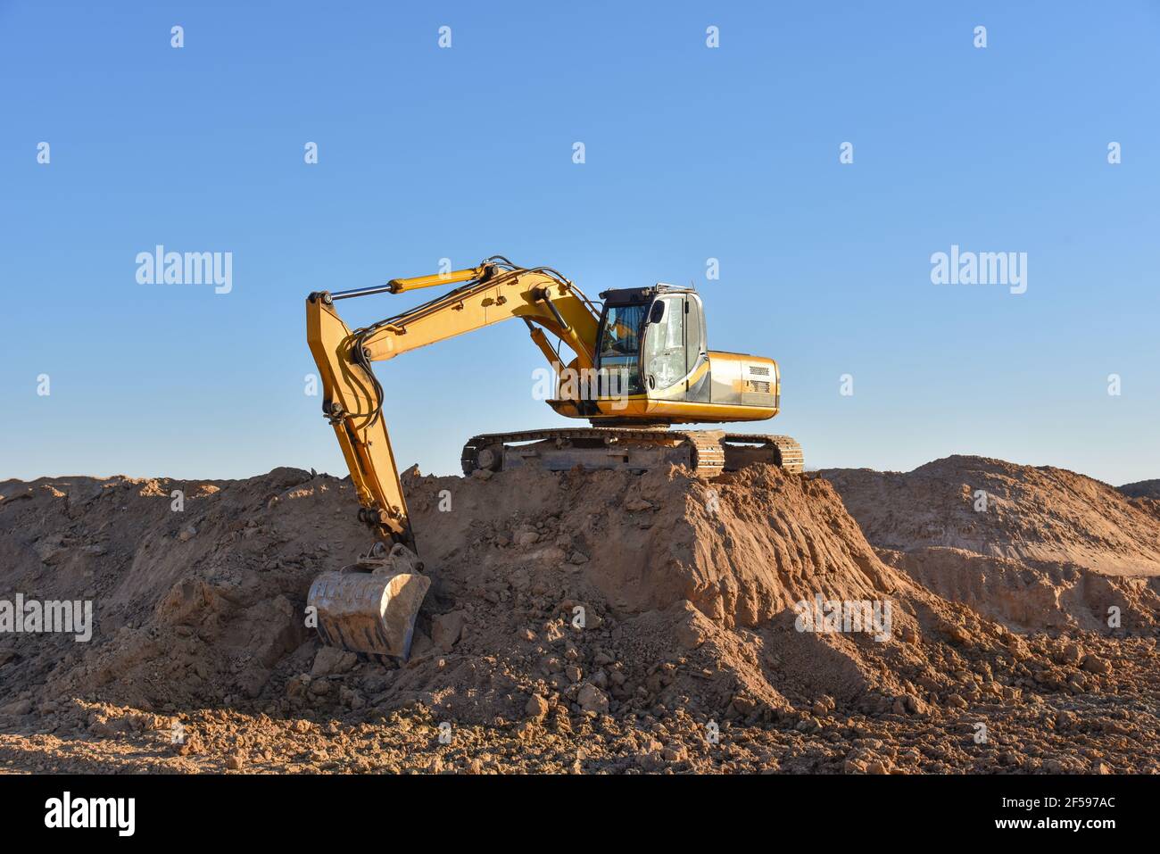 Excavator working on earthmoving at open pit mining. Yellow Backhoe ...