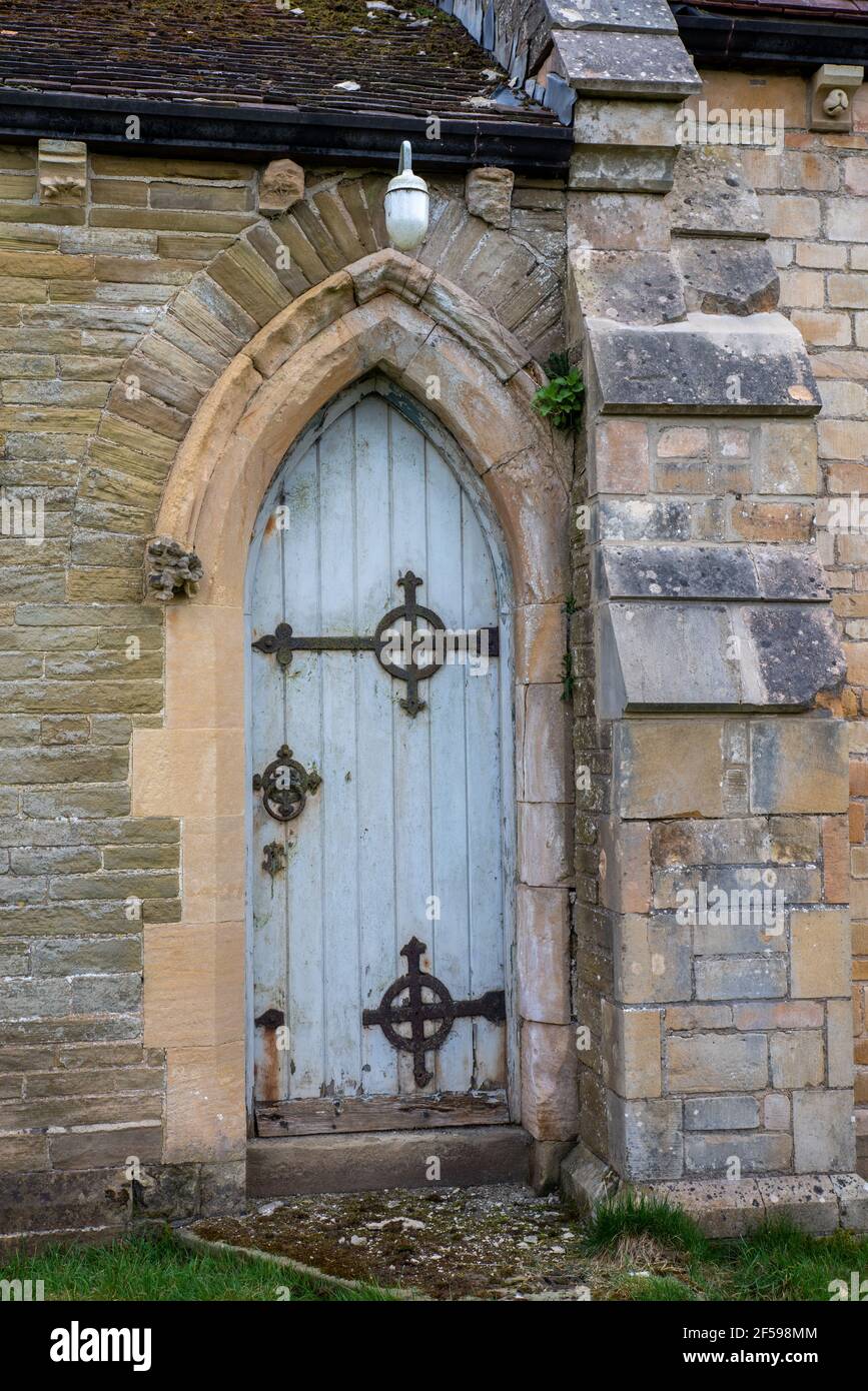 A small arched church door with ornate metal hinges and handle in ...