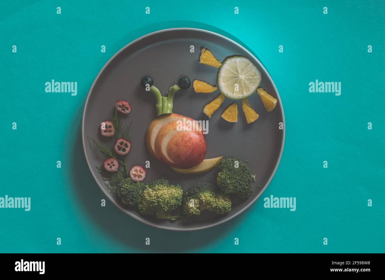 shape of snail and sun from colorful vegetables on the plate with blue ...