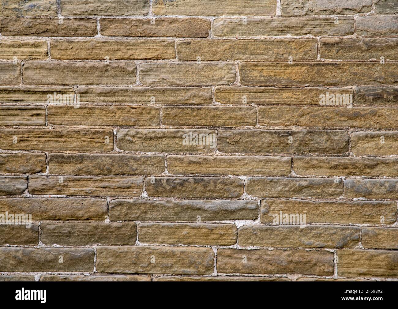 Yellow sand stone wall with uneven sized stone brickwork with white ...