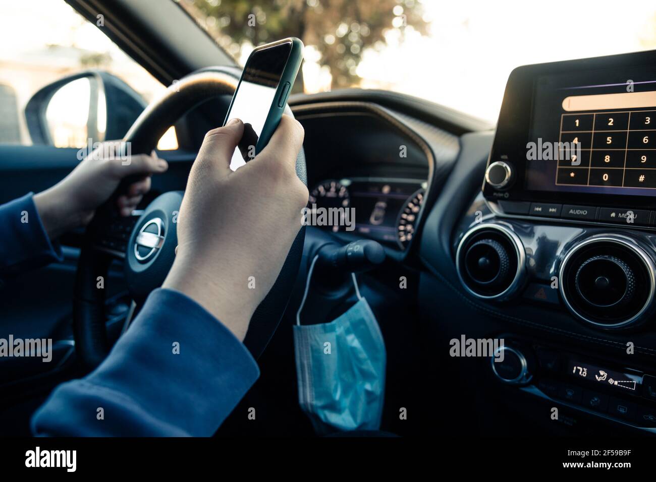 Teen drive a car and use smartphone. Young man reading messages holding ...
