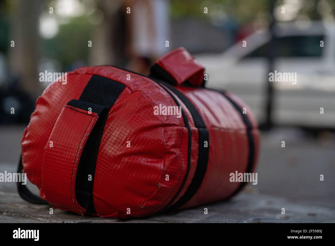 Closeup of a red punching bag on the ground in a park with a blurry ...