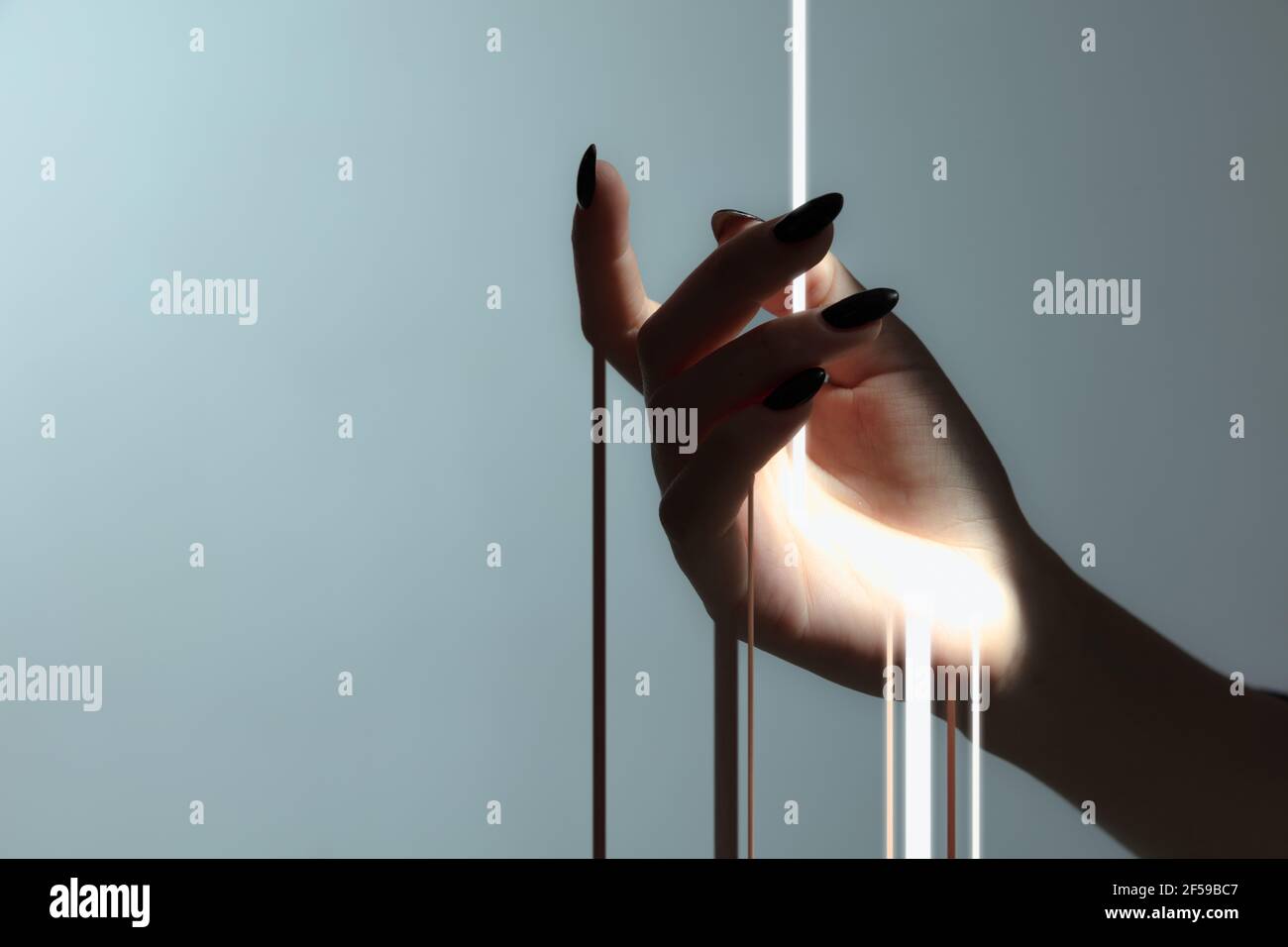 Light rays passing through delicate female hand isolated over grey ...