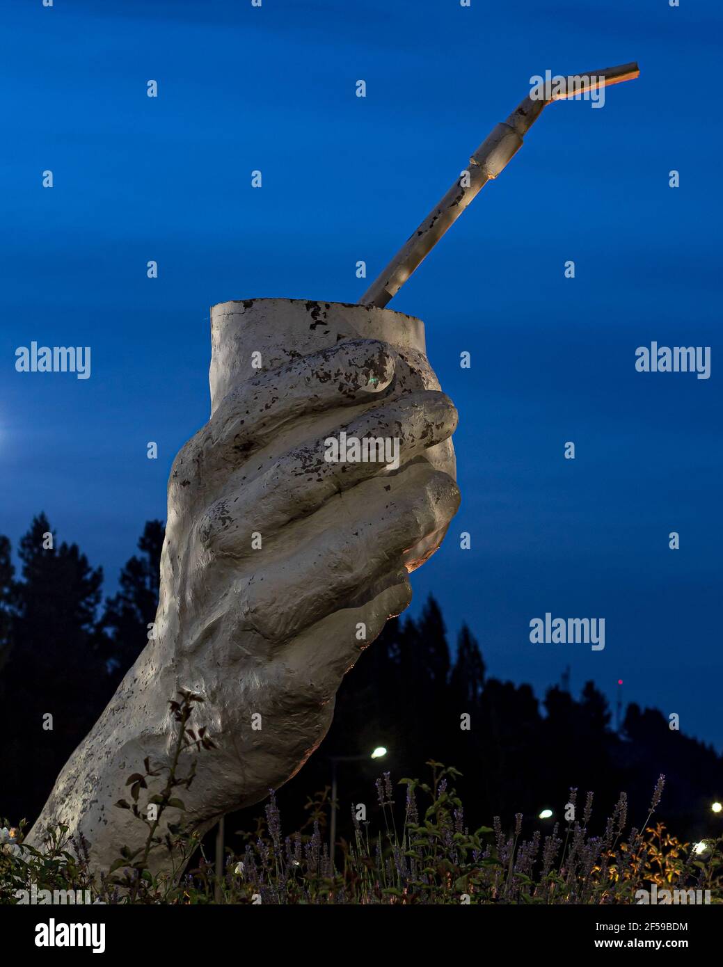 Vertical shot of a monument with hand keeping a cup in the night sky ...