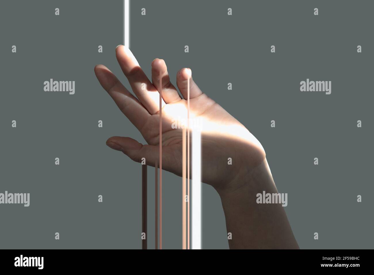 Light rays passing through delicate female hand isolated over grey ...