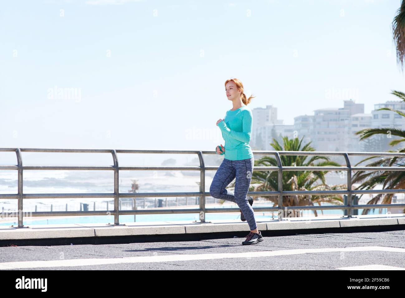 Full body portrait of attractive female runner training on path ...